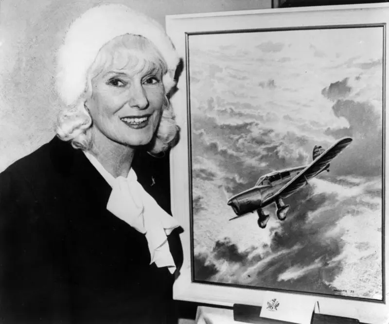 Jean Batten standing in front of the cover illustration produced by ...