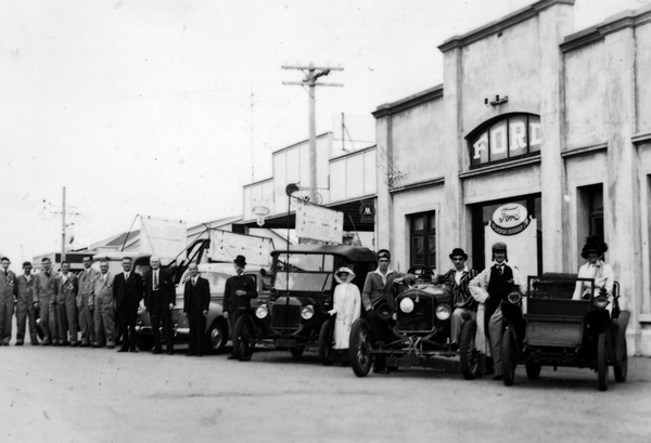 Cars and people gathered outside Gordon Hughan Ltd | Record | DigitalNZ